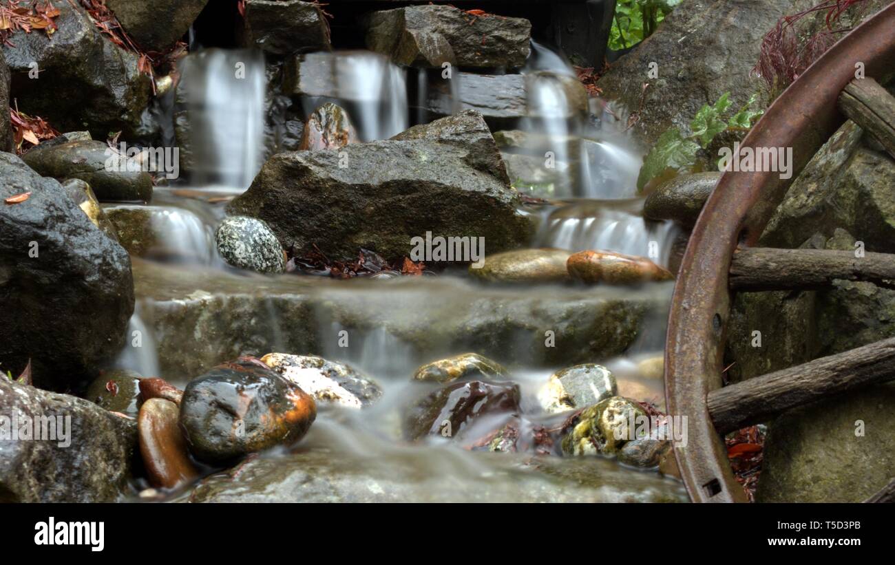 rustic rushing water fall cascading down a stone river bed focused on ...