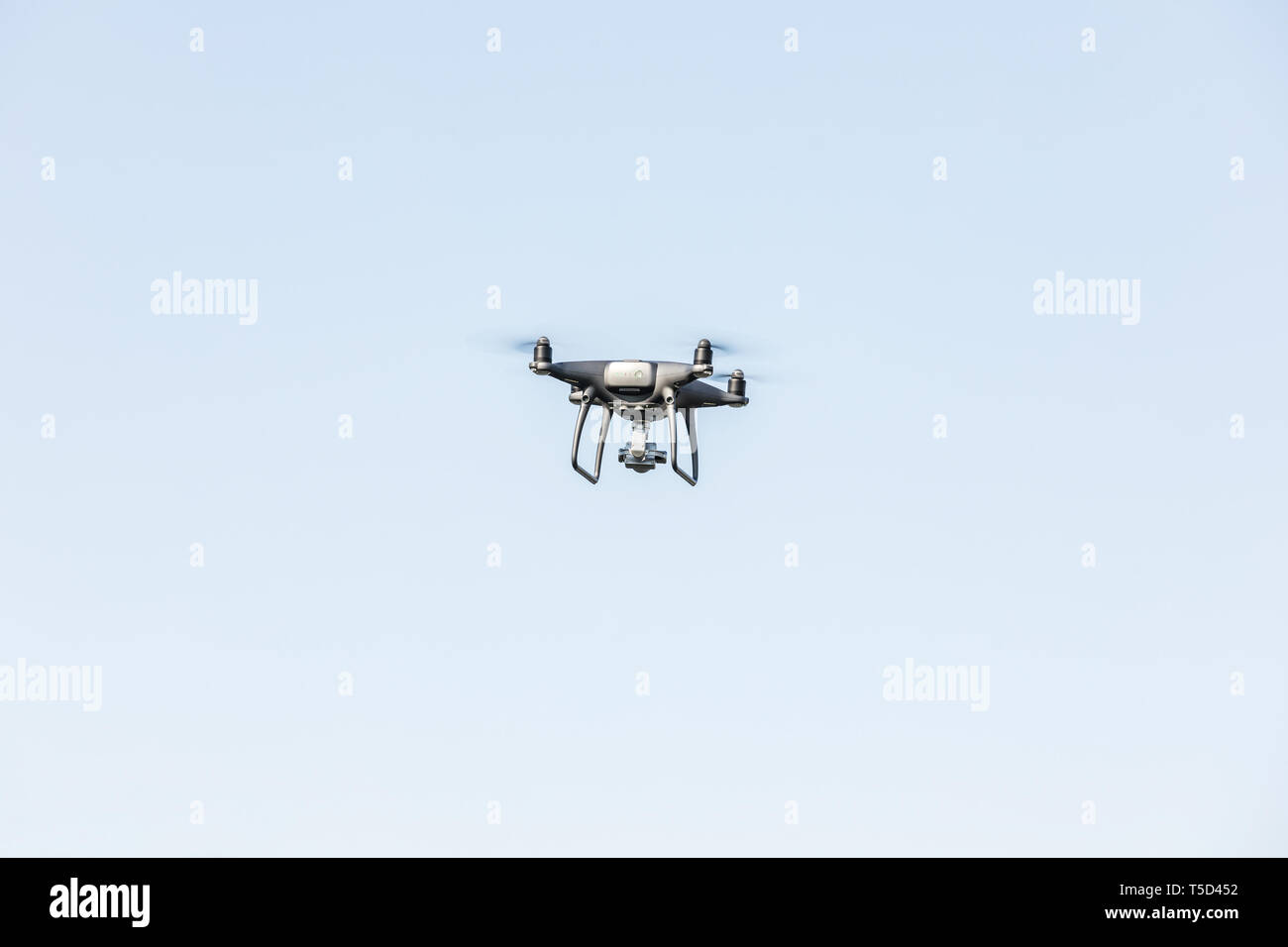 Flying drone on the blue sky. Modern silver drone flying Stock Photo ...