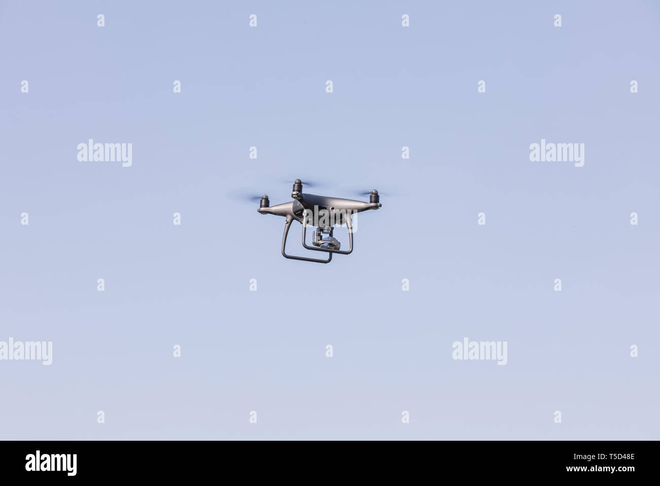 Flying drone on the blue sky. Modern silver drone flying Stock Photo ...