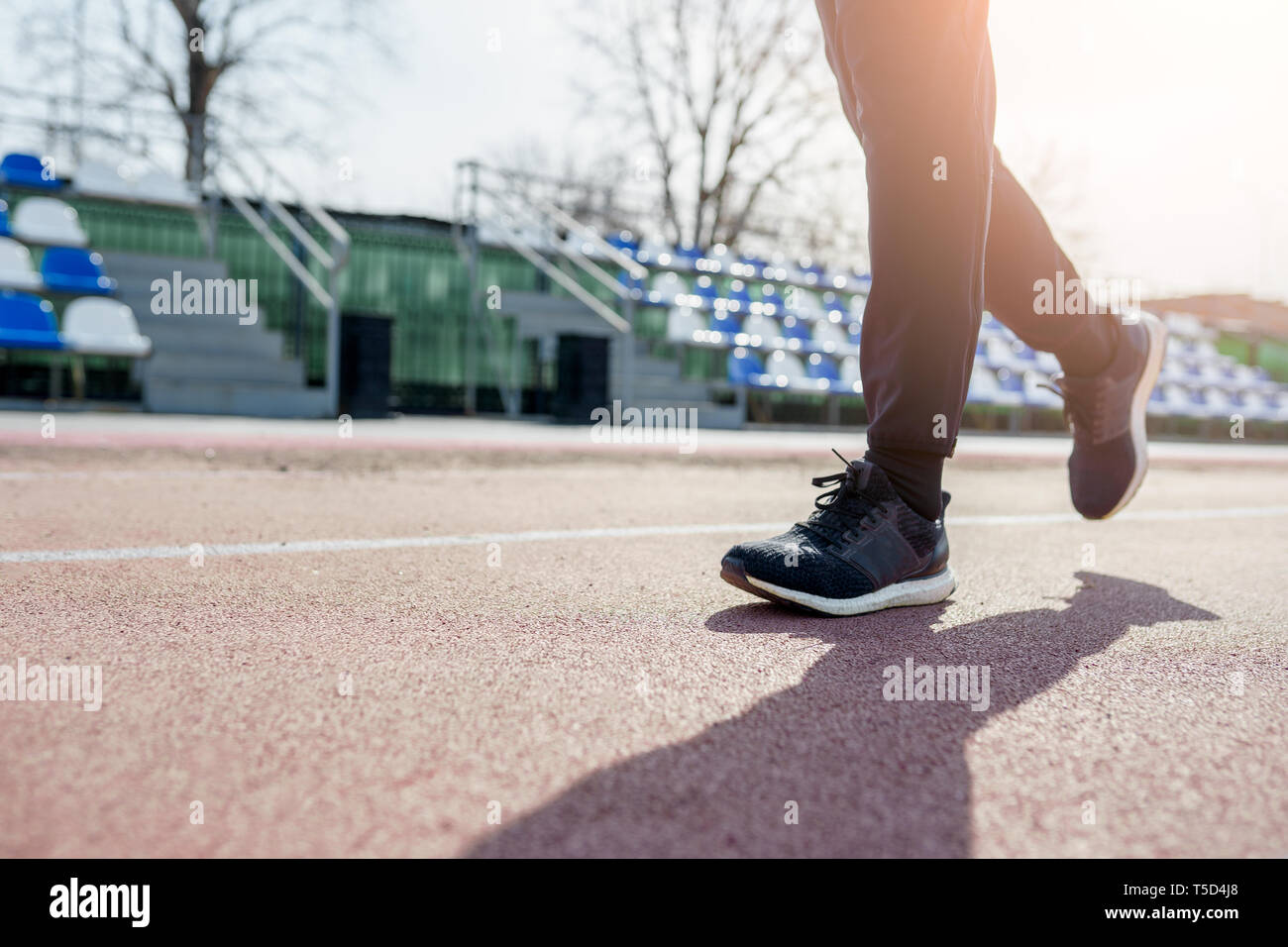 Photo from side of legs of athlete running through stadium Stock Photo ...