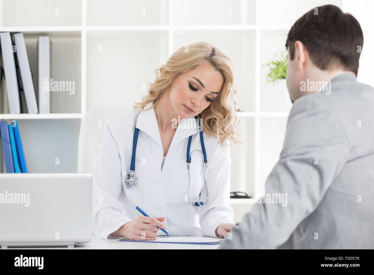 Doctor with patient reading a contract document in clinical office or ...
