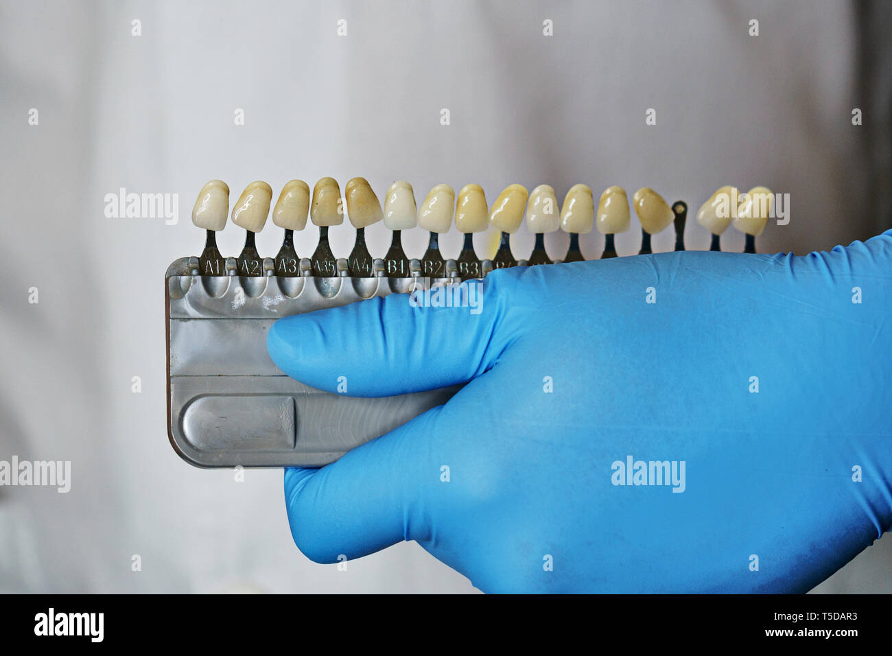 Dentist is holding comparative scale for teeth whitening and selection ...