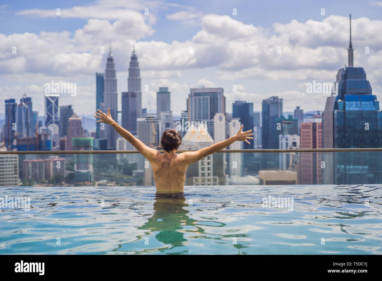Man relax in swimming pool in sunrise, on rooftop in the city. Rich ...