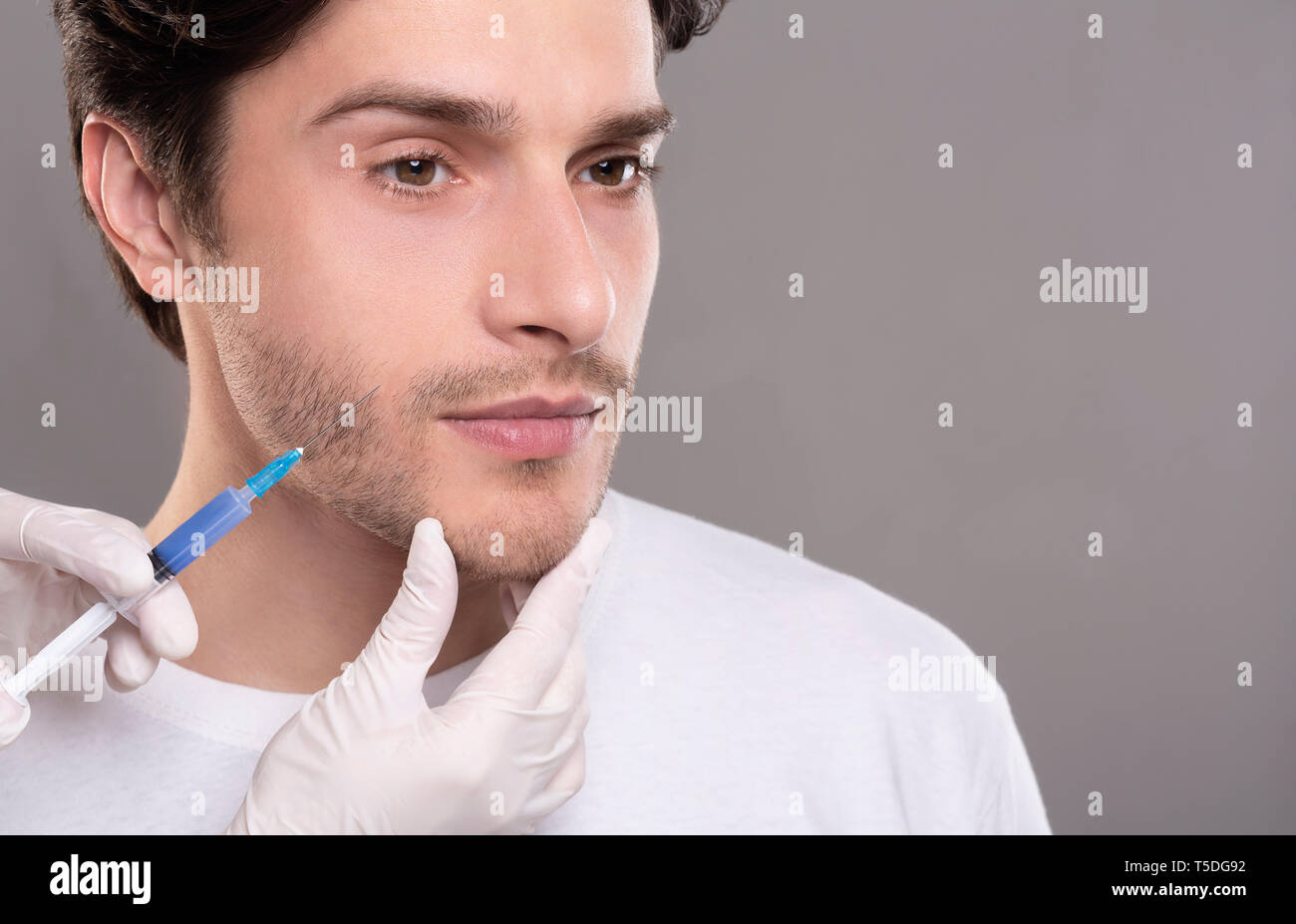 Beautician doing injection to young man face Stock Photo - Alamy