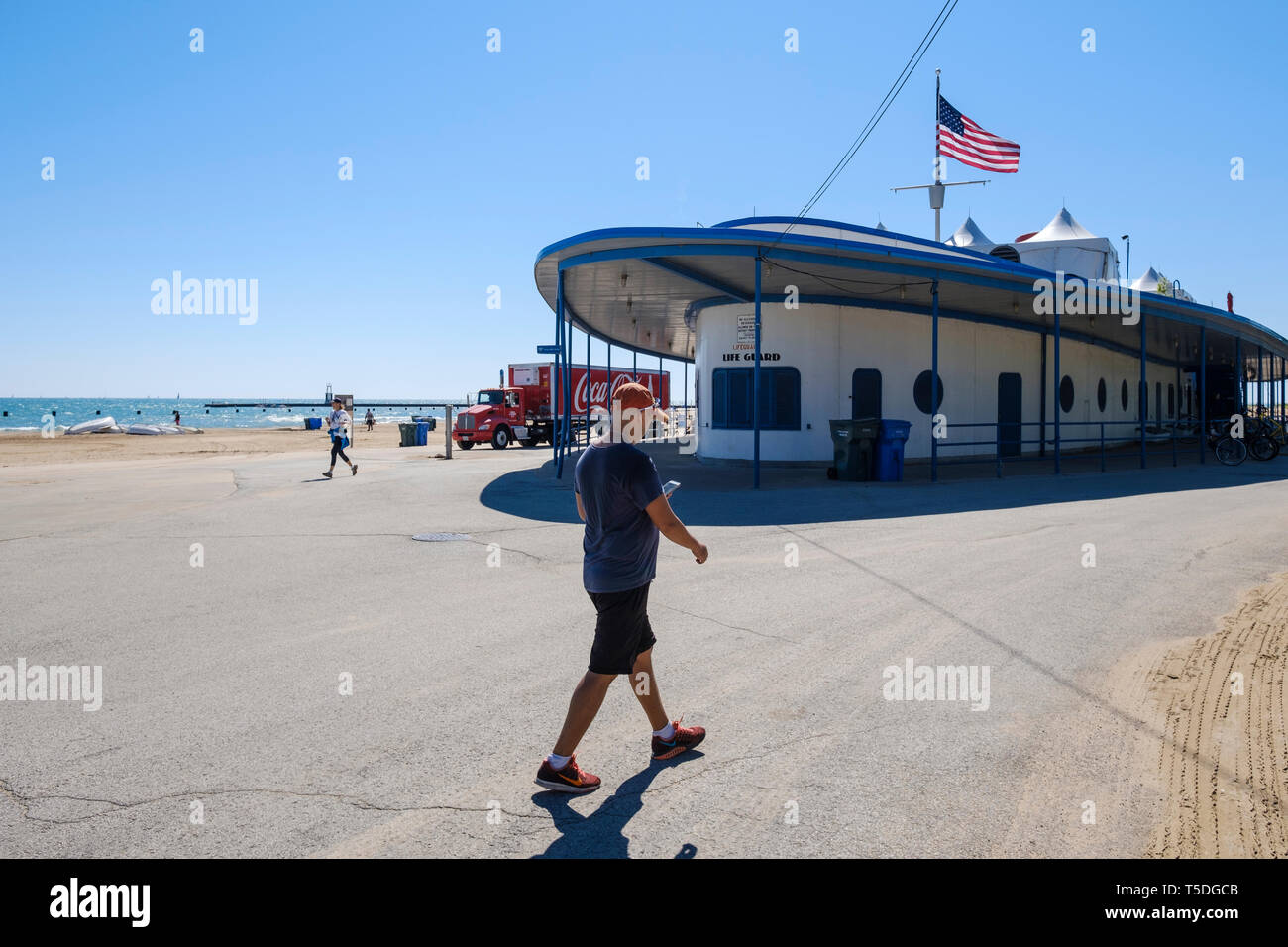 White man walking while checking his mobile next to Castaways Bar in ...