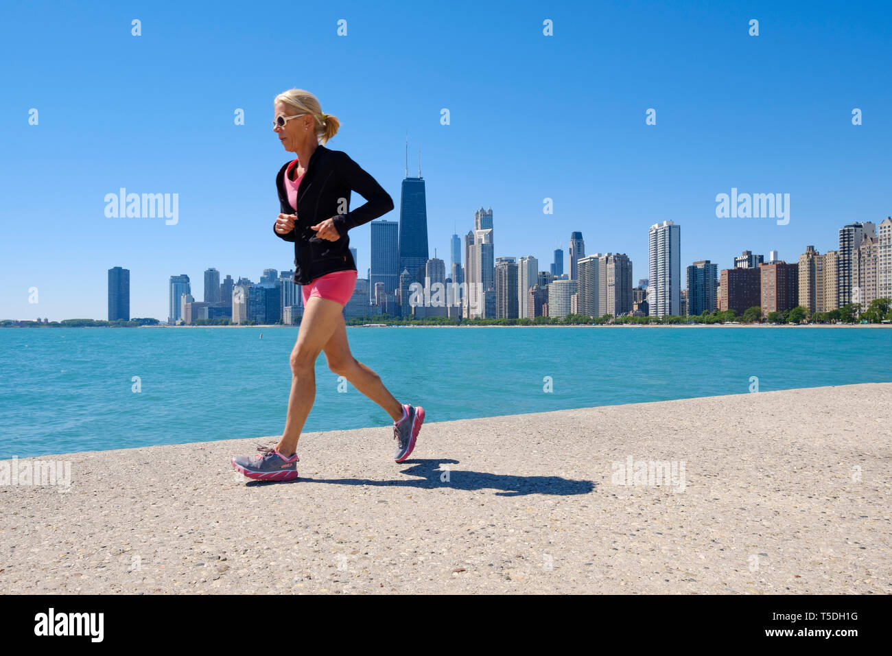 Mature white woman running on Chicago Lakefront Trail with the Chicago ...