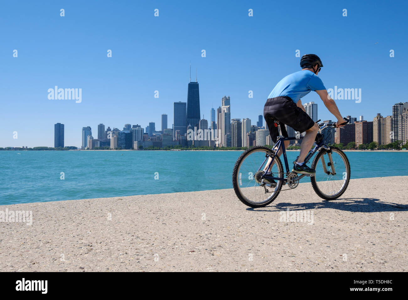 White man cycling on Chicago Lakefront Trail with the Chicago skyline ...