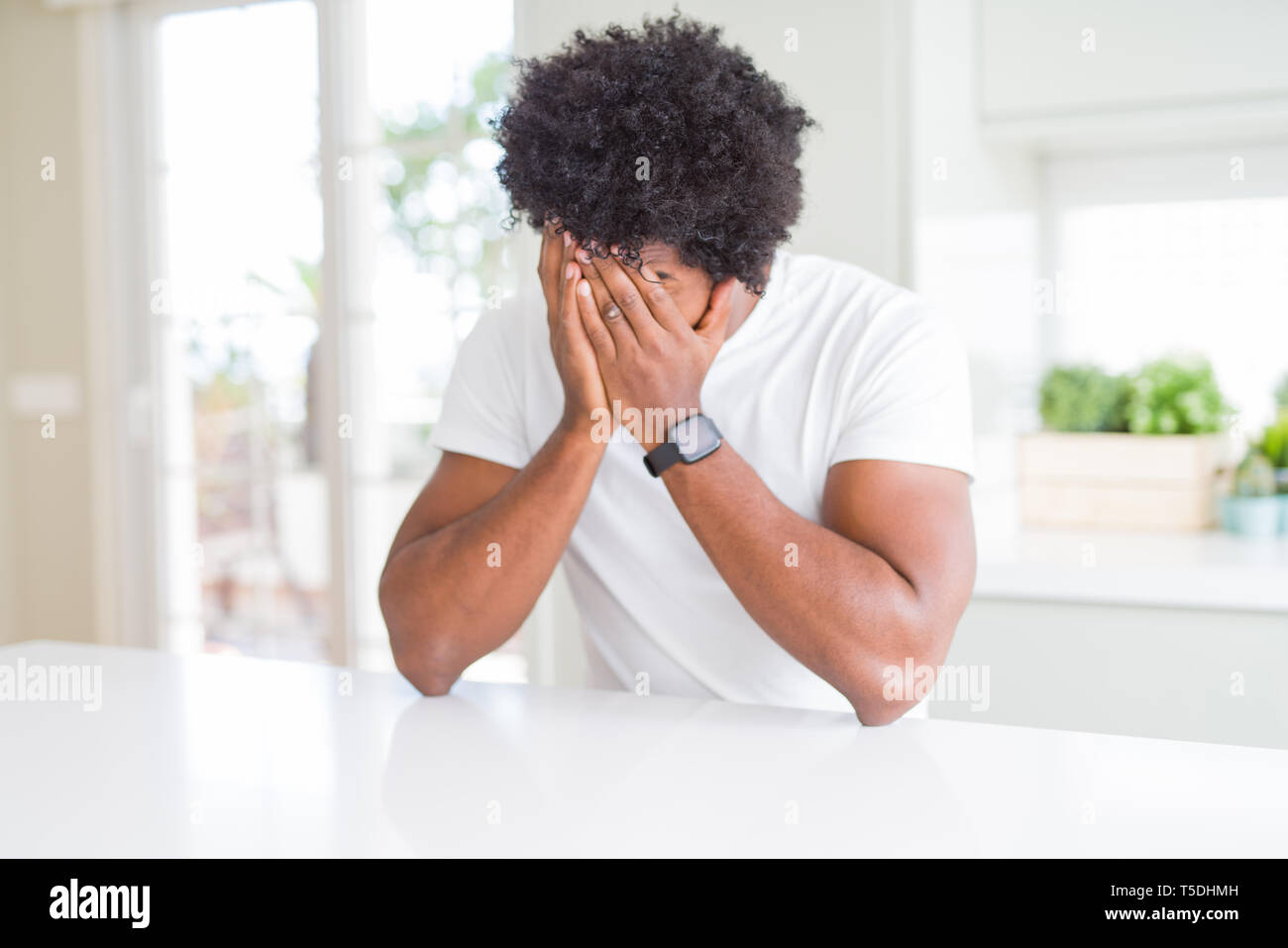 Young african american man wearing casual white t-shirt sitting at home ...