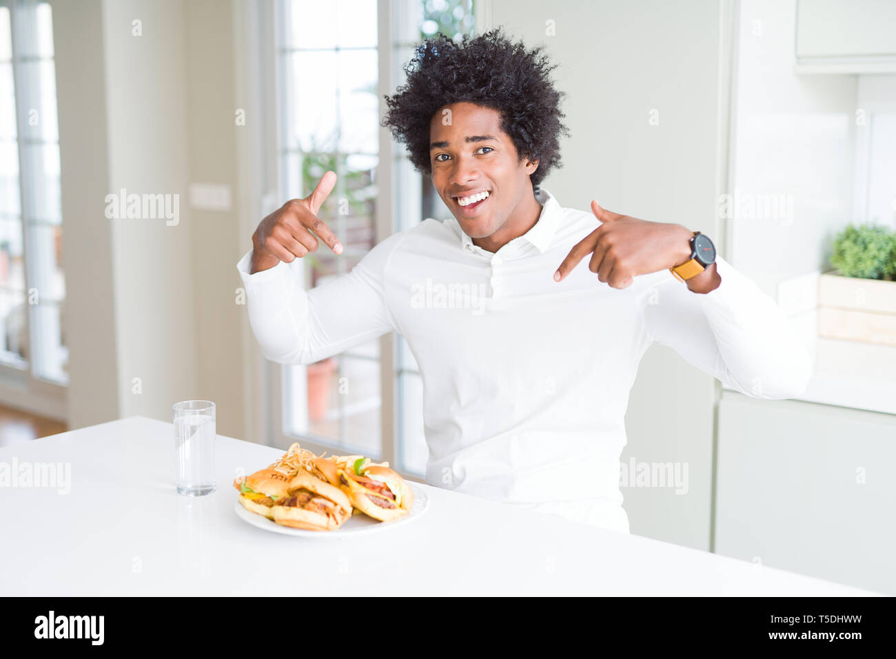 African American hungry man eating hamburger for lunch looking ...