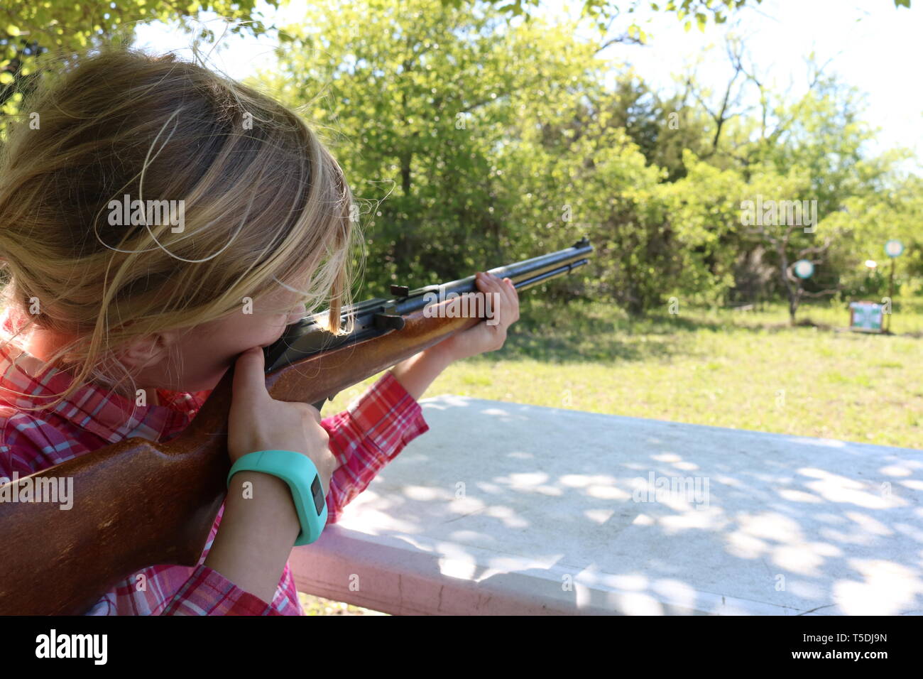 Girl with blond hair doing target practice with a 22 rifle Stock Photo ...