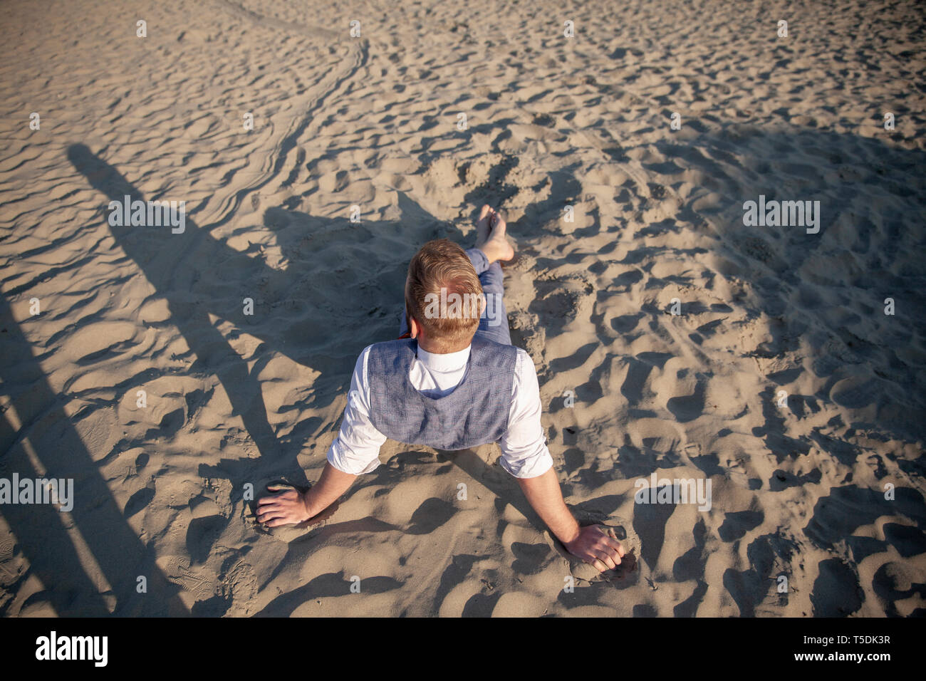 one young man, elevated view from above. relaxing on a beach in sand ...