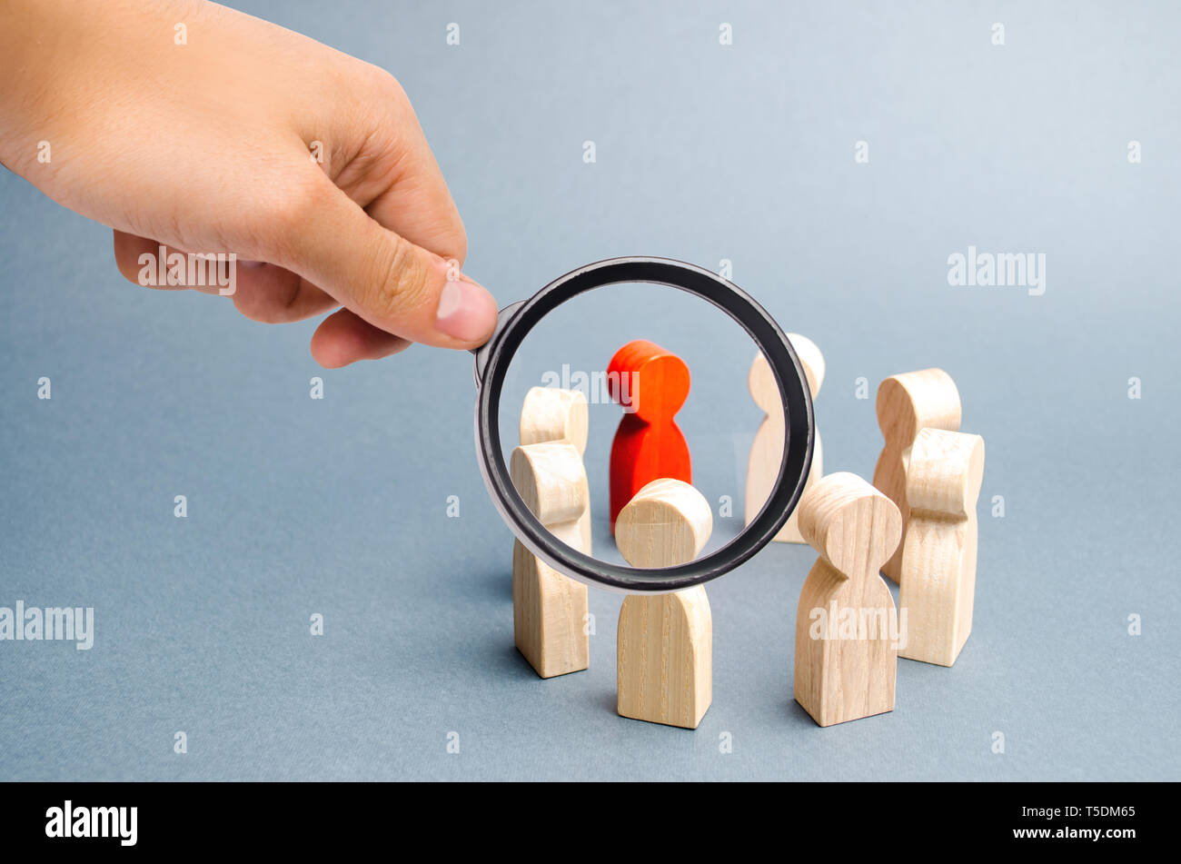 Magnifying glass is looking at the People stand in a circle on a gray ...