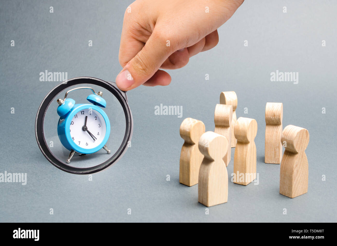 Magnifying glass is looking at the blue clock. Crowd of people looks at ...