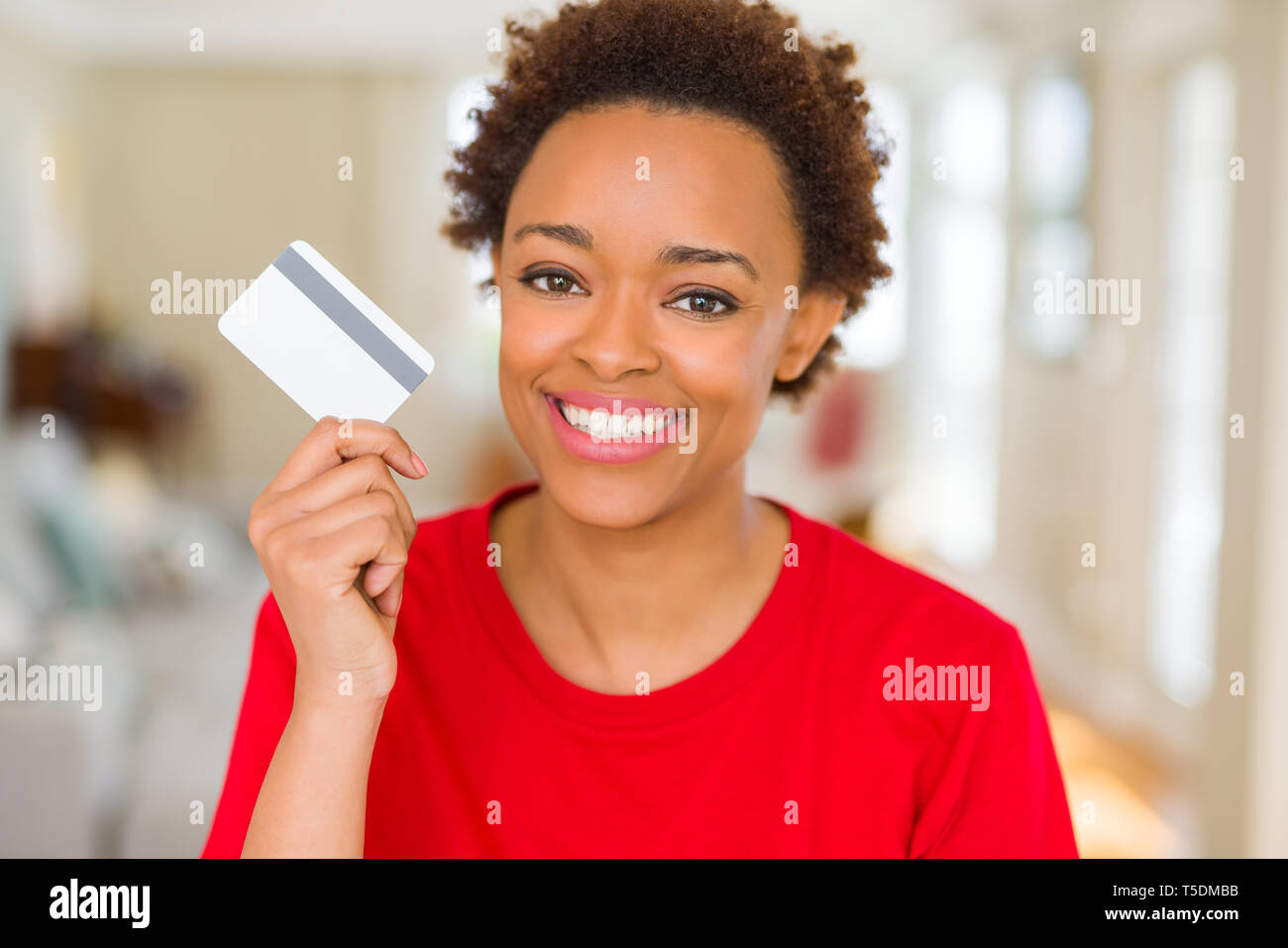 Young african american woman holding credit card with a happy face ...