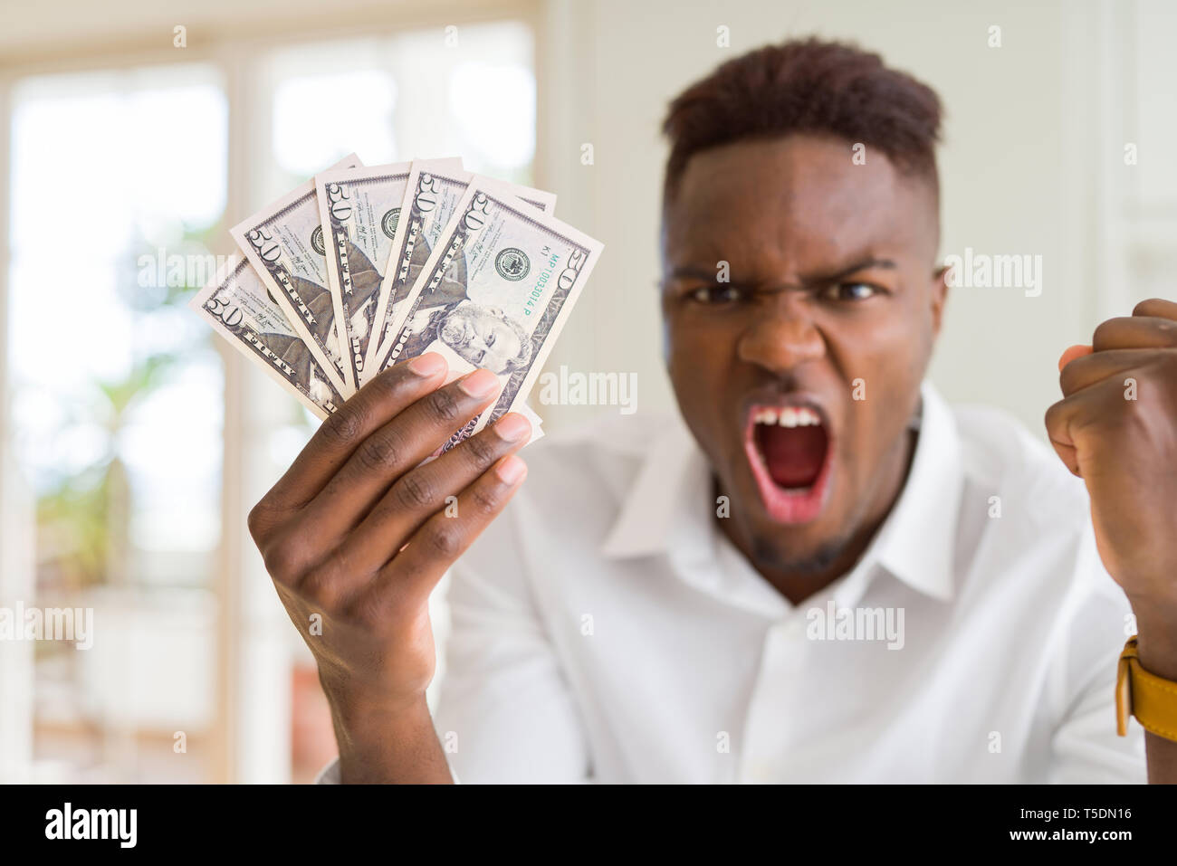 African american man holding fifty dollars bank notes annoyed and ...