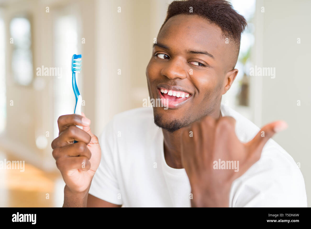 African american man holding toothbrush pointing and showing with thumb ...