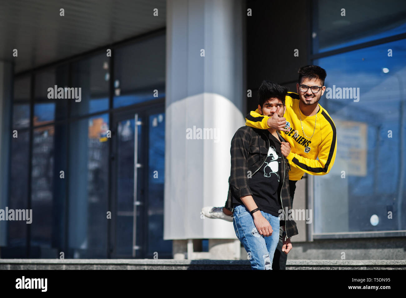 Two asian guys posed against new modern building Stock Photo - Alamy
