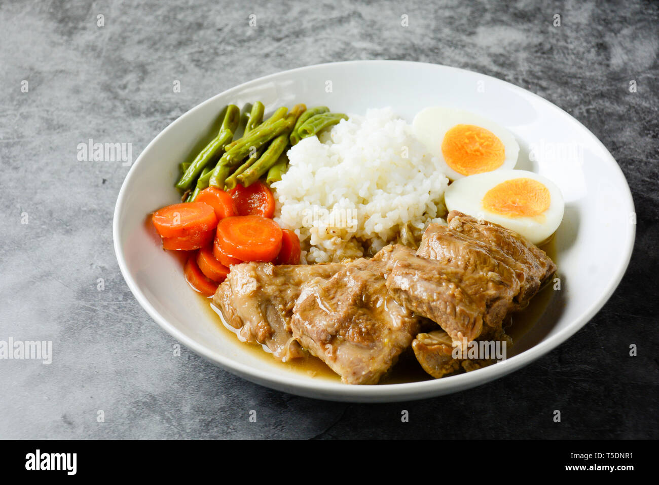 Baked pork ribs with rice, boiled egg and vegetable Stock Photo - Alamy