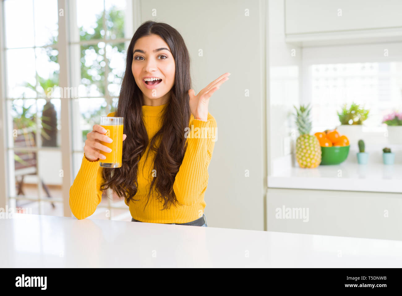 Young woman drinking a glass of fresh orange juice very happy and ...