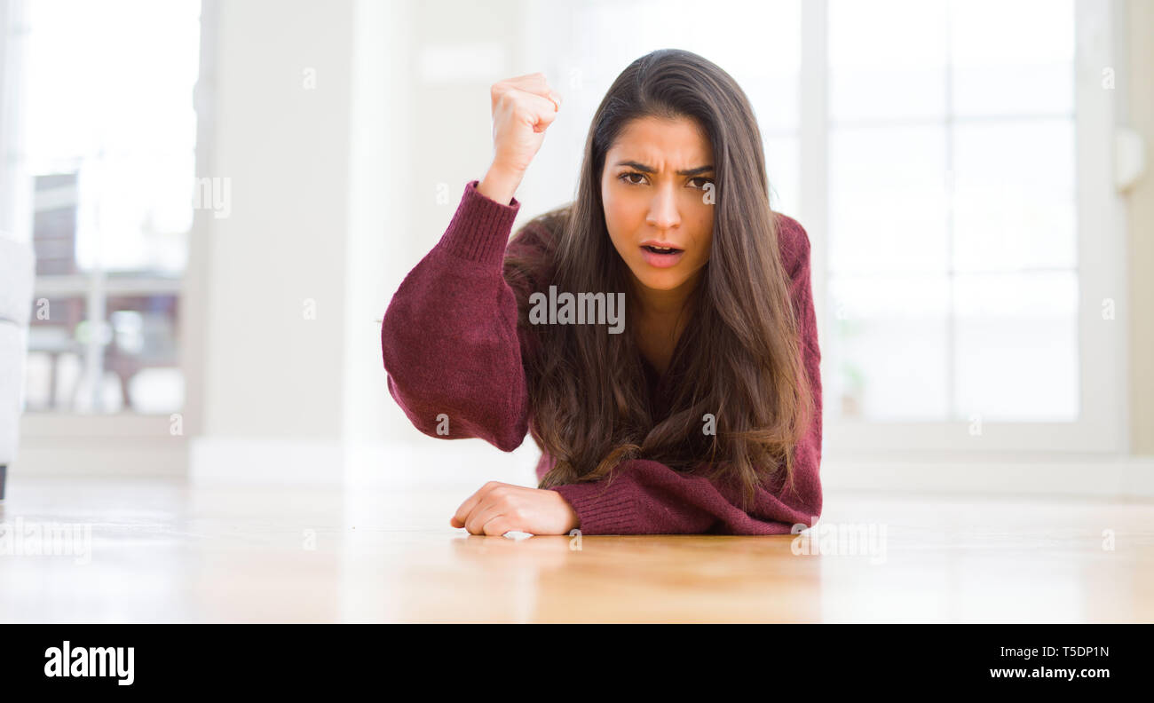 Young beautiful woman lying on the floor at home annoyed and frustrated ...