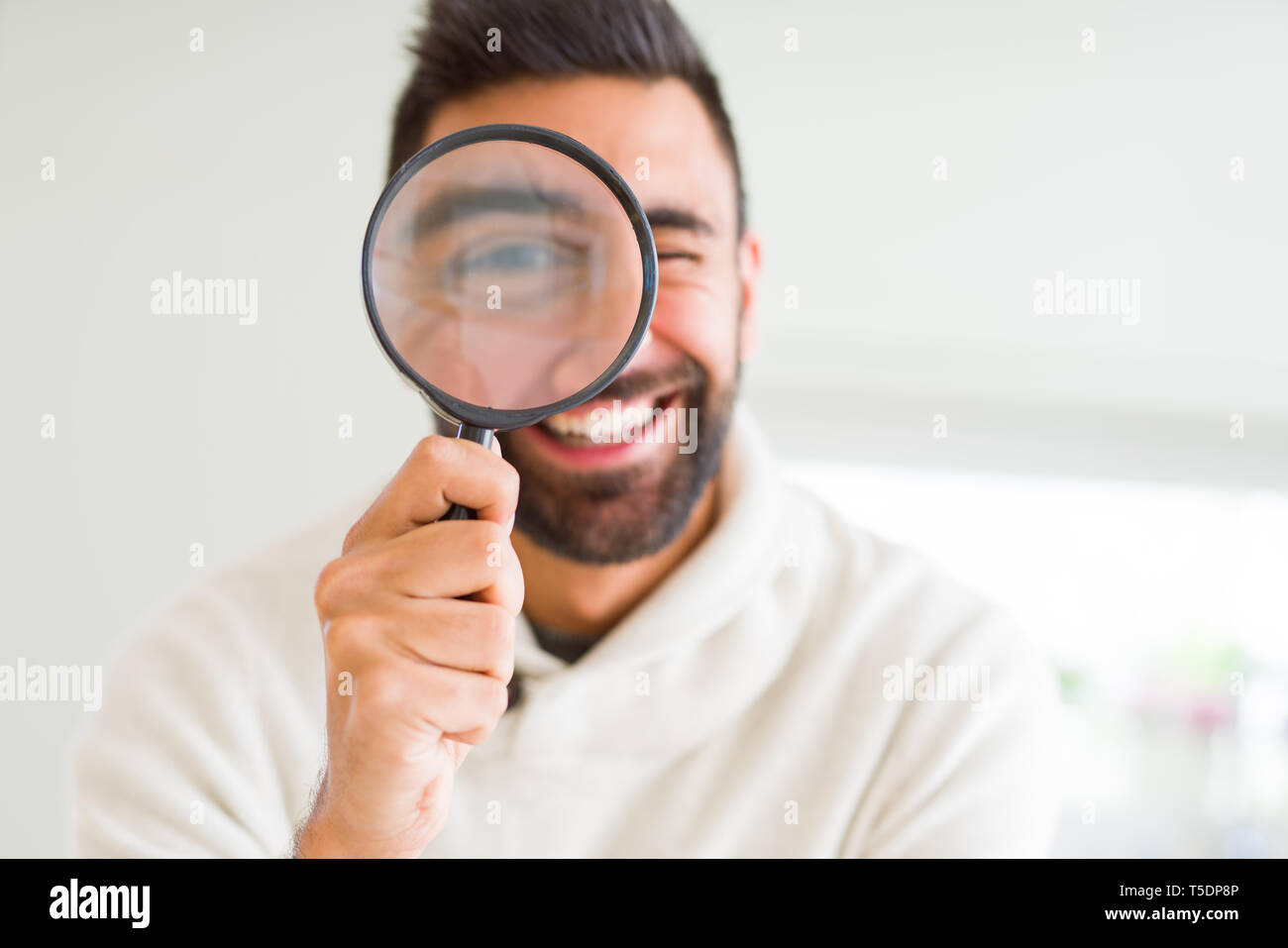 Handsome man using magnifying glass, doing funny faces Stock Photo - Alamy