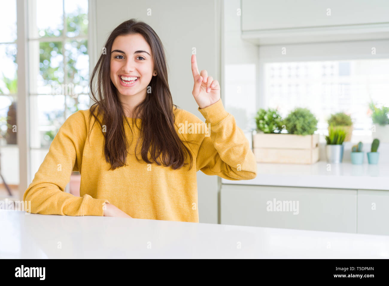 Beautiful young woman wearing yellow sweater showing and pointing up ...
