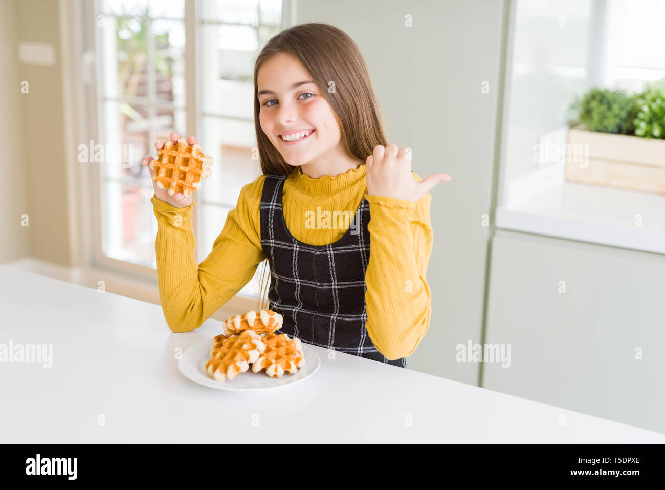 Beautiful young girl kid eating Belgian waffle pastry pointing and ...