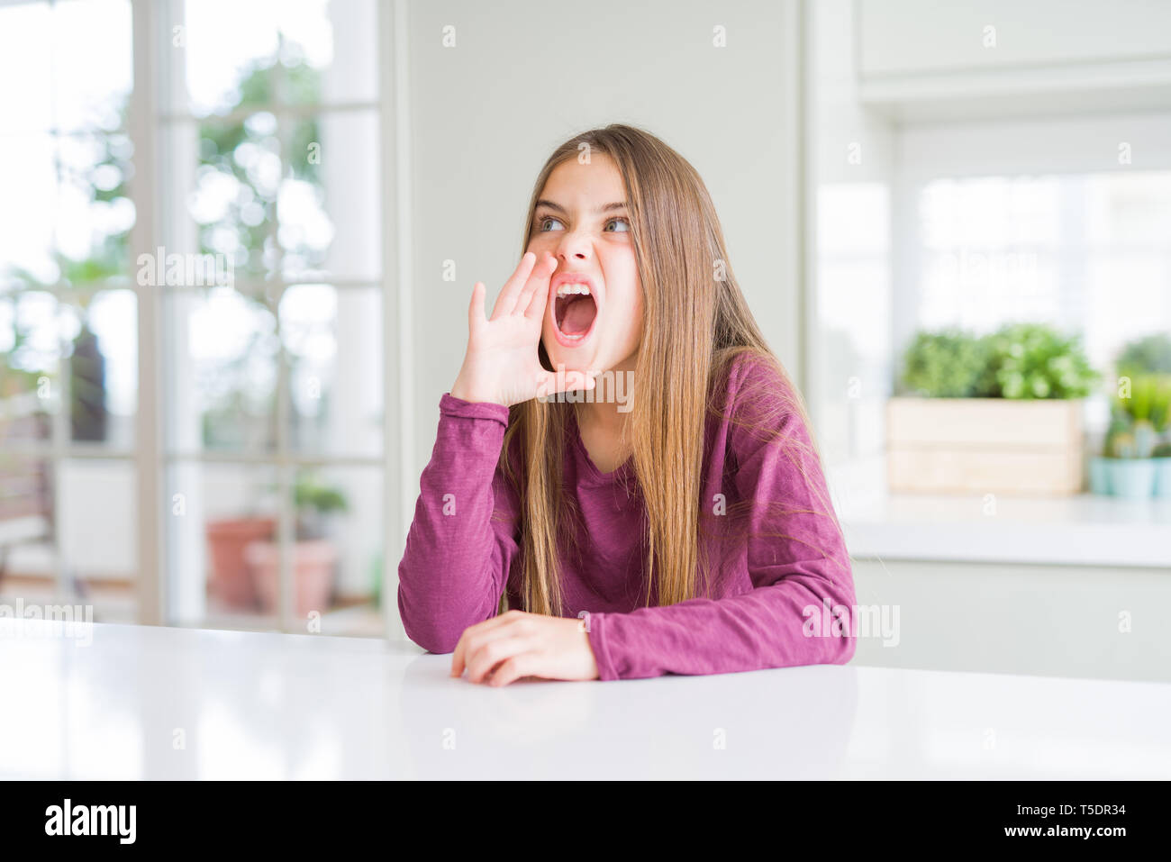 Beautiful young girl kid on white table shouting and screaming loud to ...