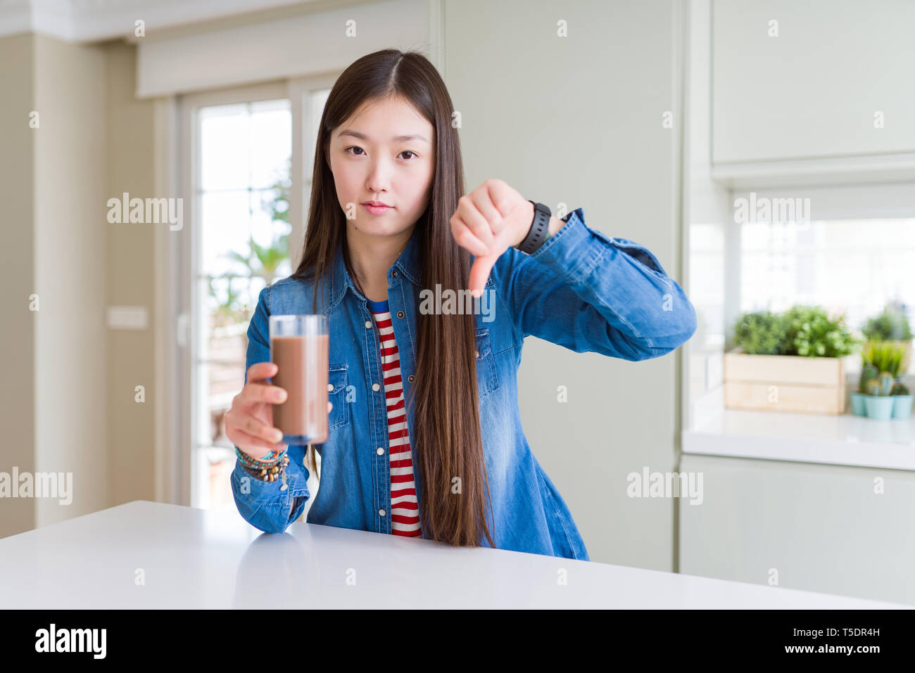 Beautiful Asian woman drinking a fresh glass of chocolate milkshake ...