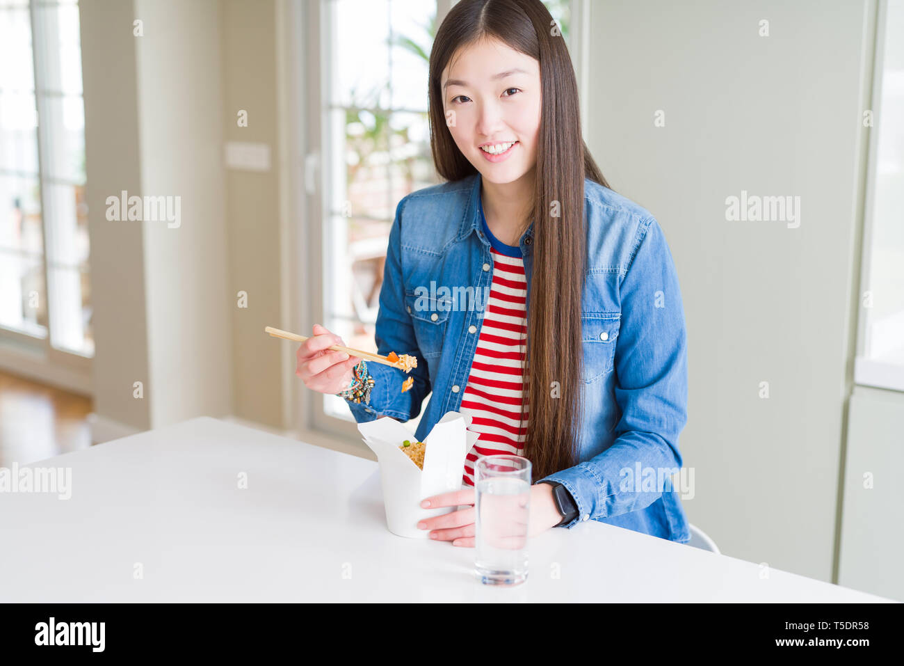 Beautiful Asian woman eating asian rice in delivery box with a happy ...