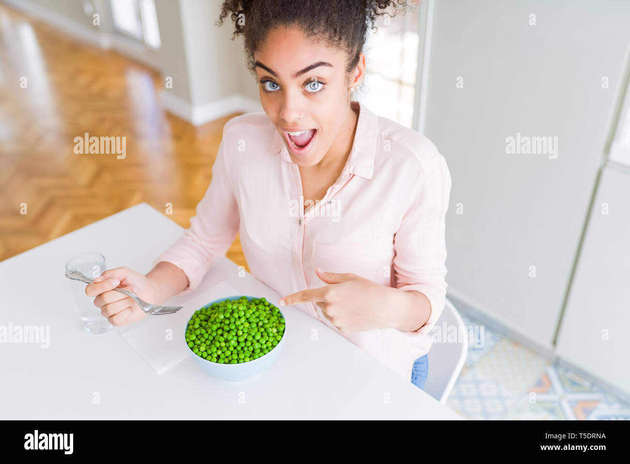 Young african american girl eating healthy green peas very happy ...