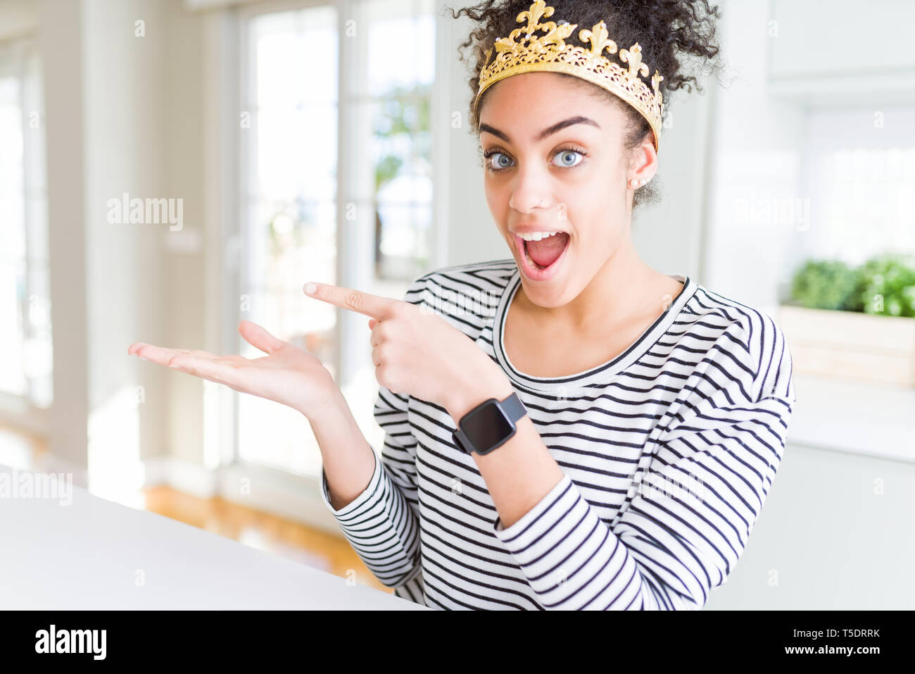 Young african american girl wearing golden queen crown on head amazed ...