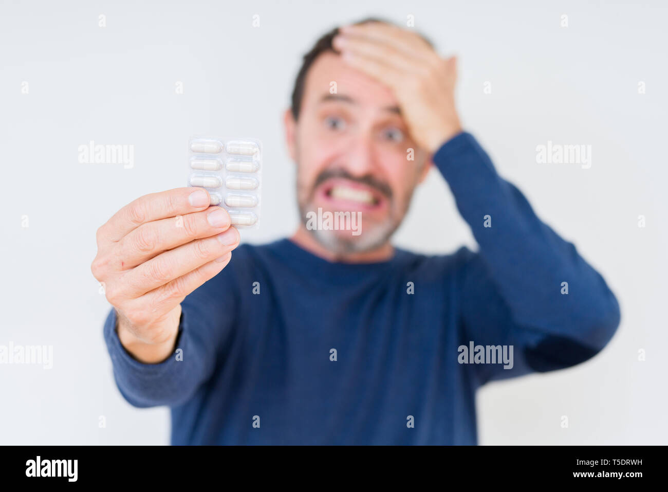 Senior man holding pharmaceutical pills over isolated background ...