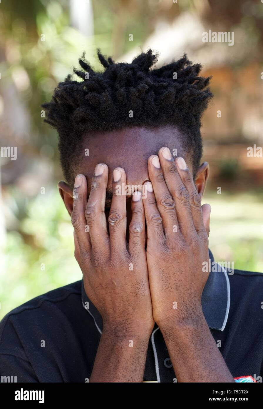 Namibian man of the Ovambo tribe holding hands in front of his face ...