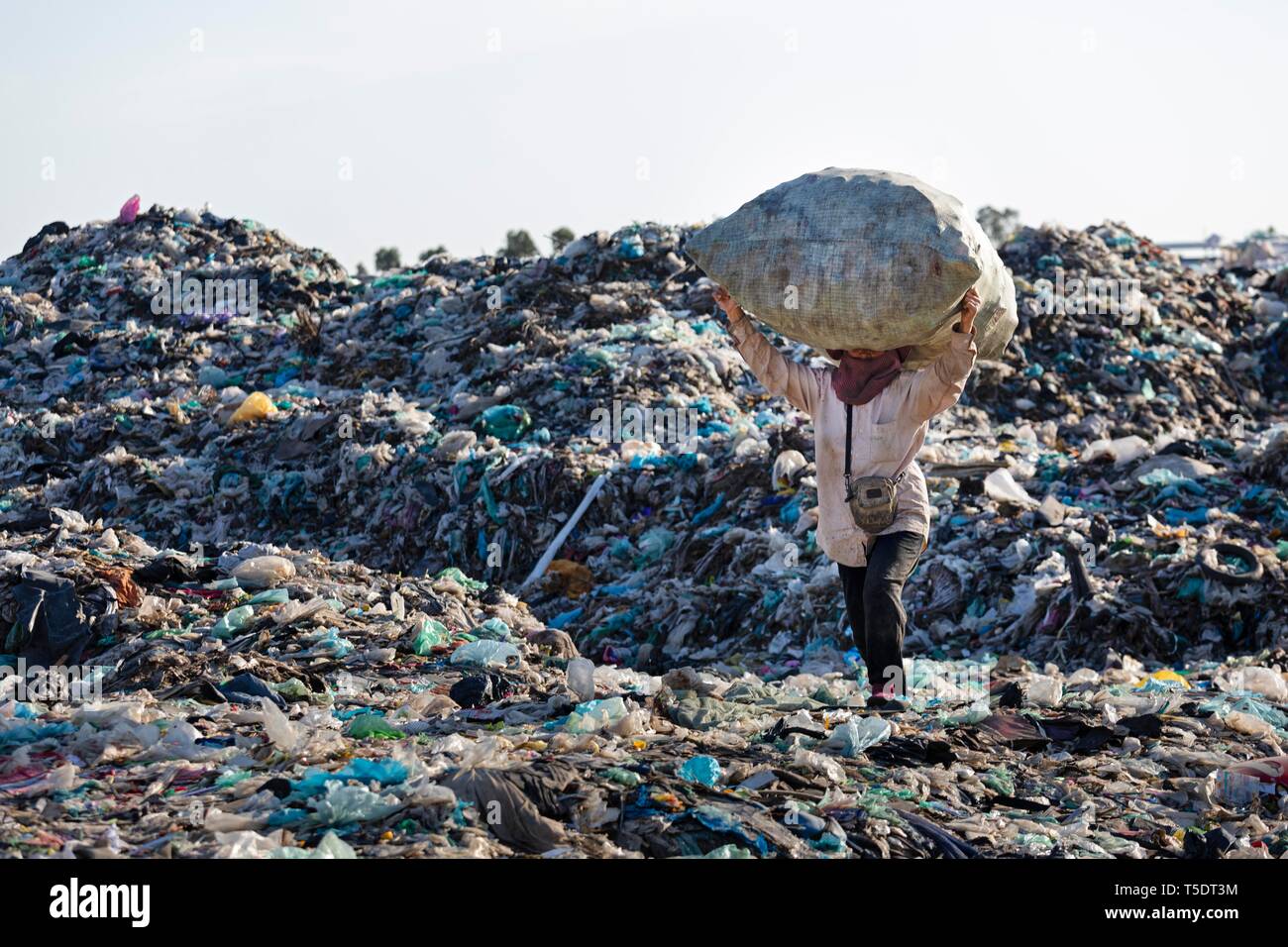 Garbage collector on garbage dump, garbage mountain with plastic ...