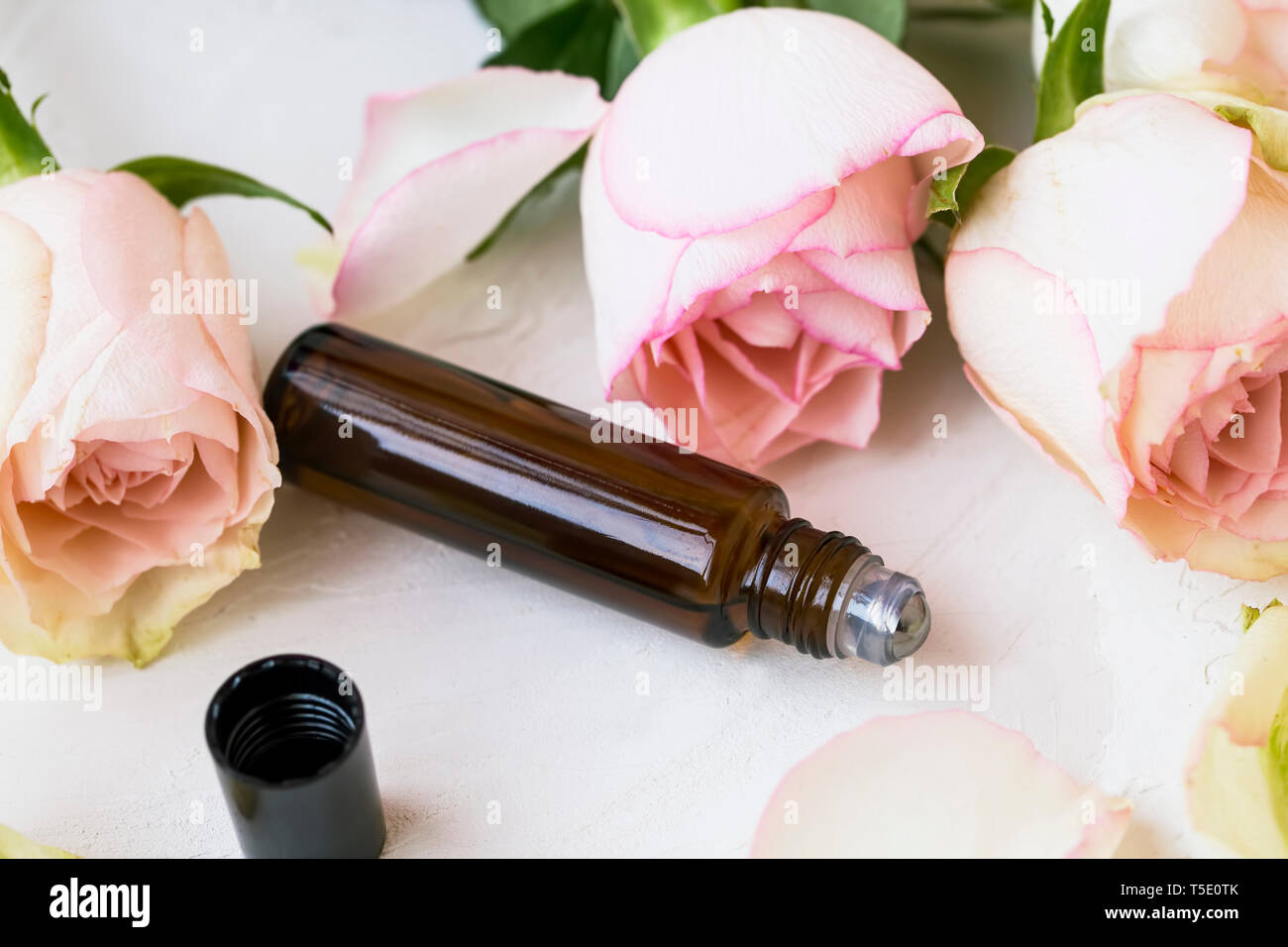 Rose oil roll on bottle closeup with rose flowers, soft delicate flower ...