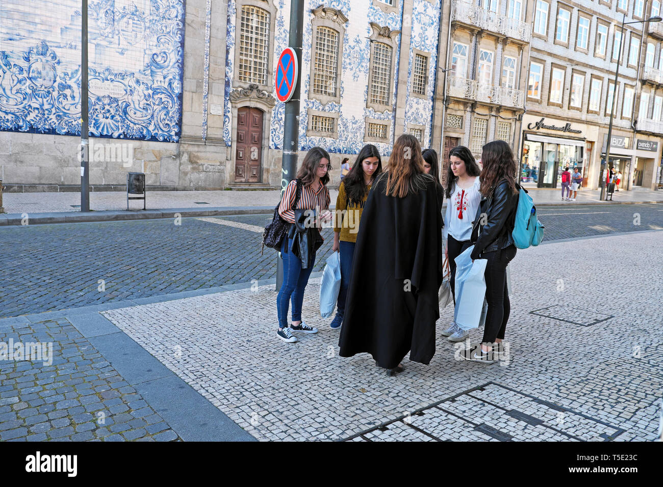 University female student in black cloak talking to students in street ...