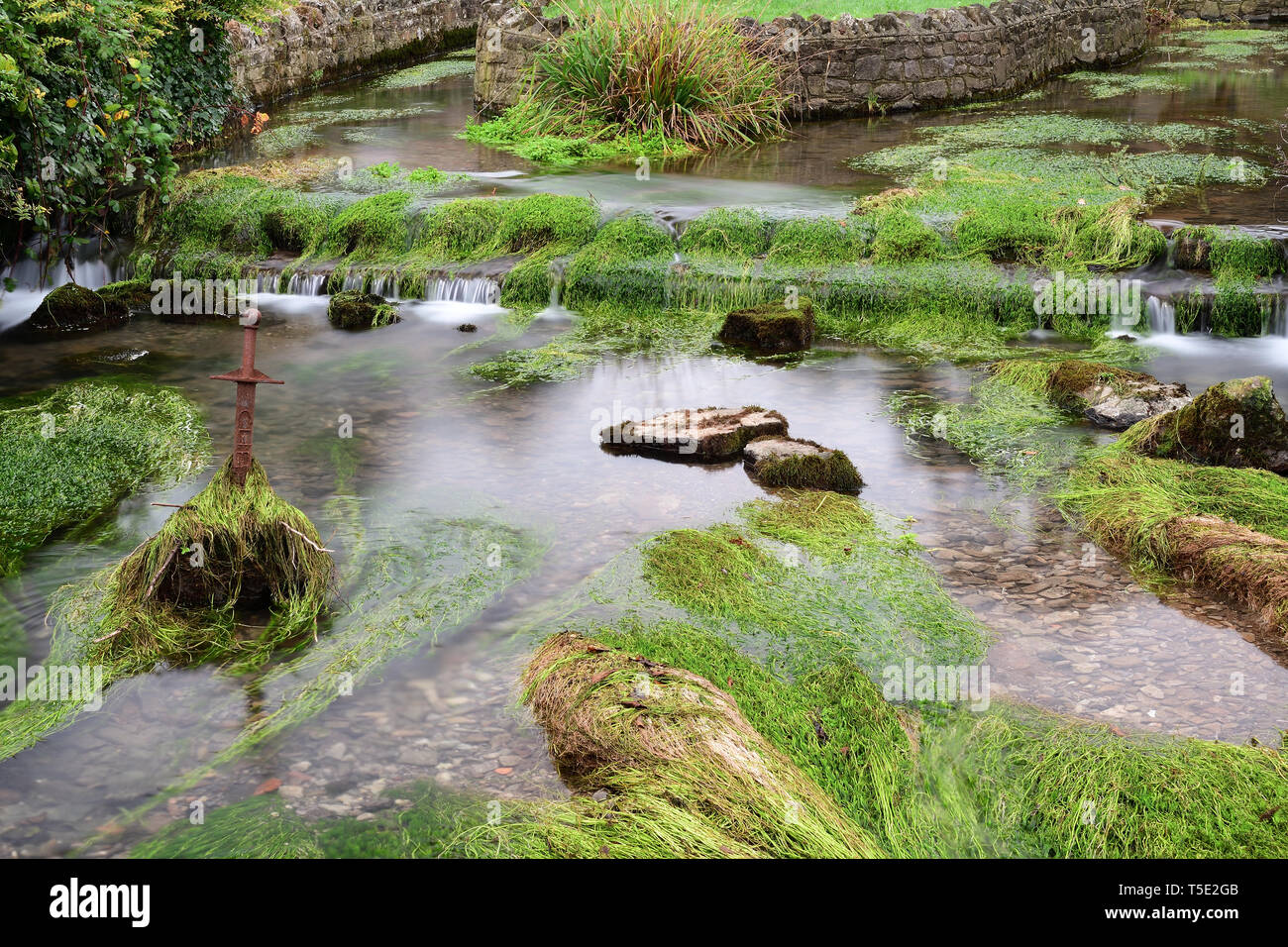 Long exposure of the river flowing past a sword sticking out of the ...