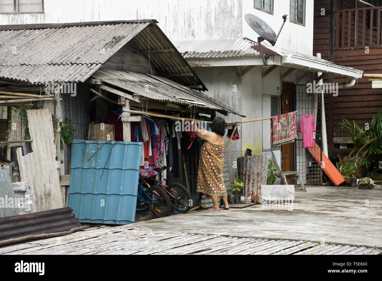 Woman hanging laundry to dry in communal area of Bidayuh tribal ...