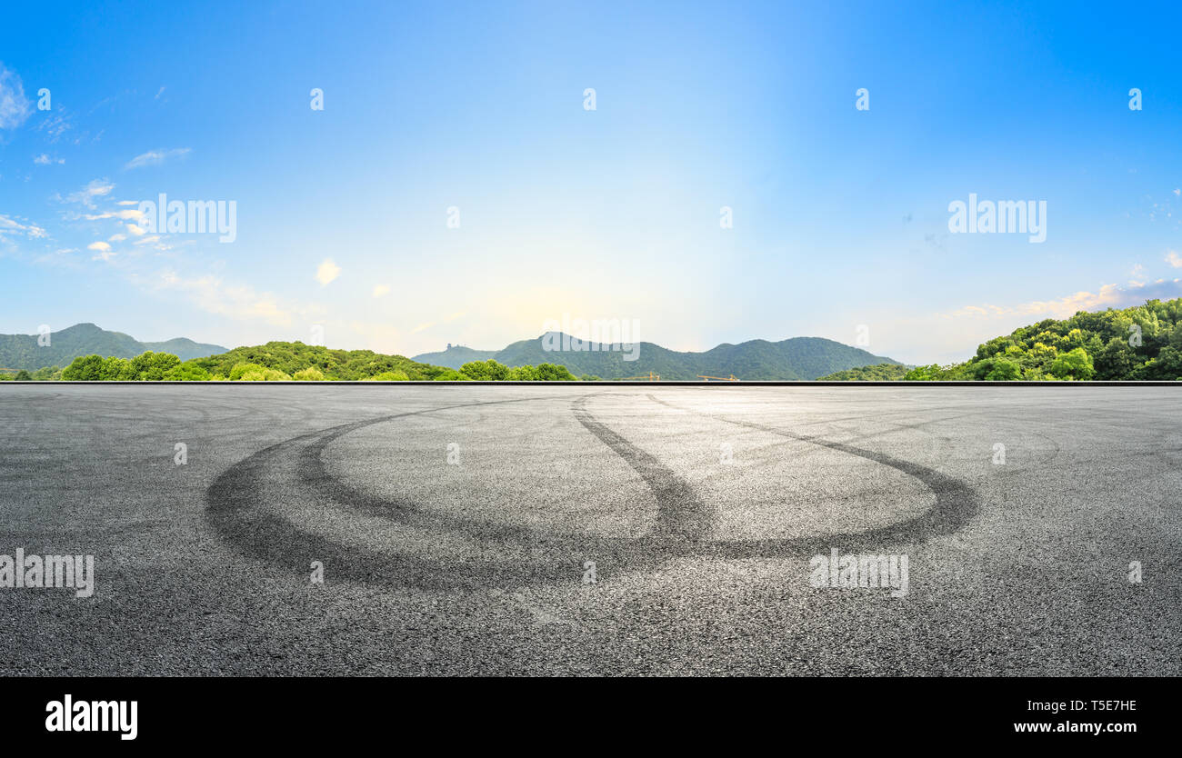 Asphalt race track ground and mountains with beautiful clouds at sunset ...