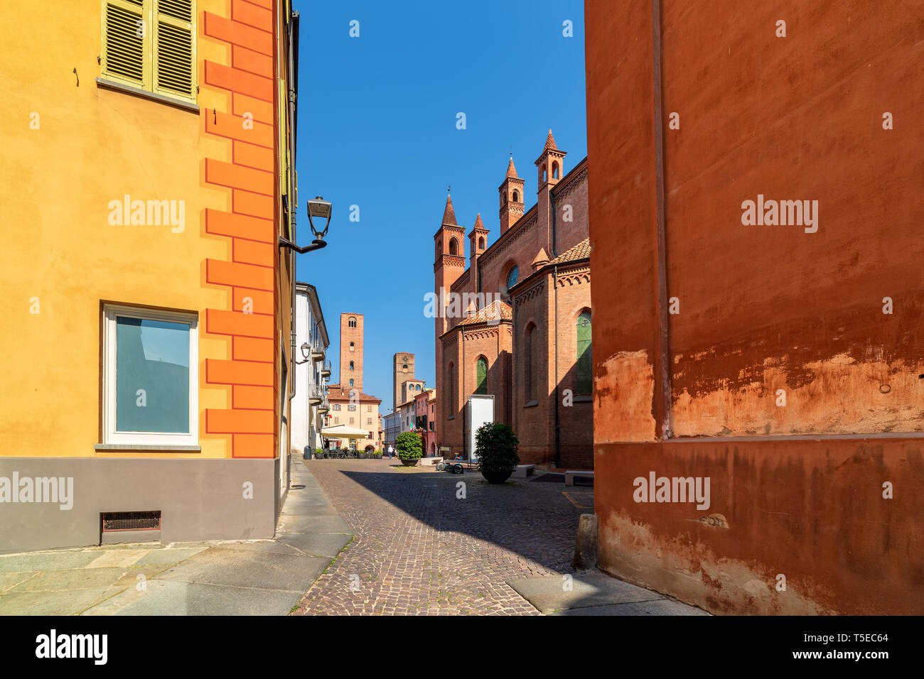 Cobblestone street among colorful walls as medieval towers and Duomo ...