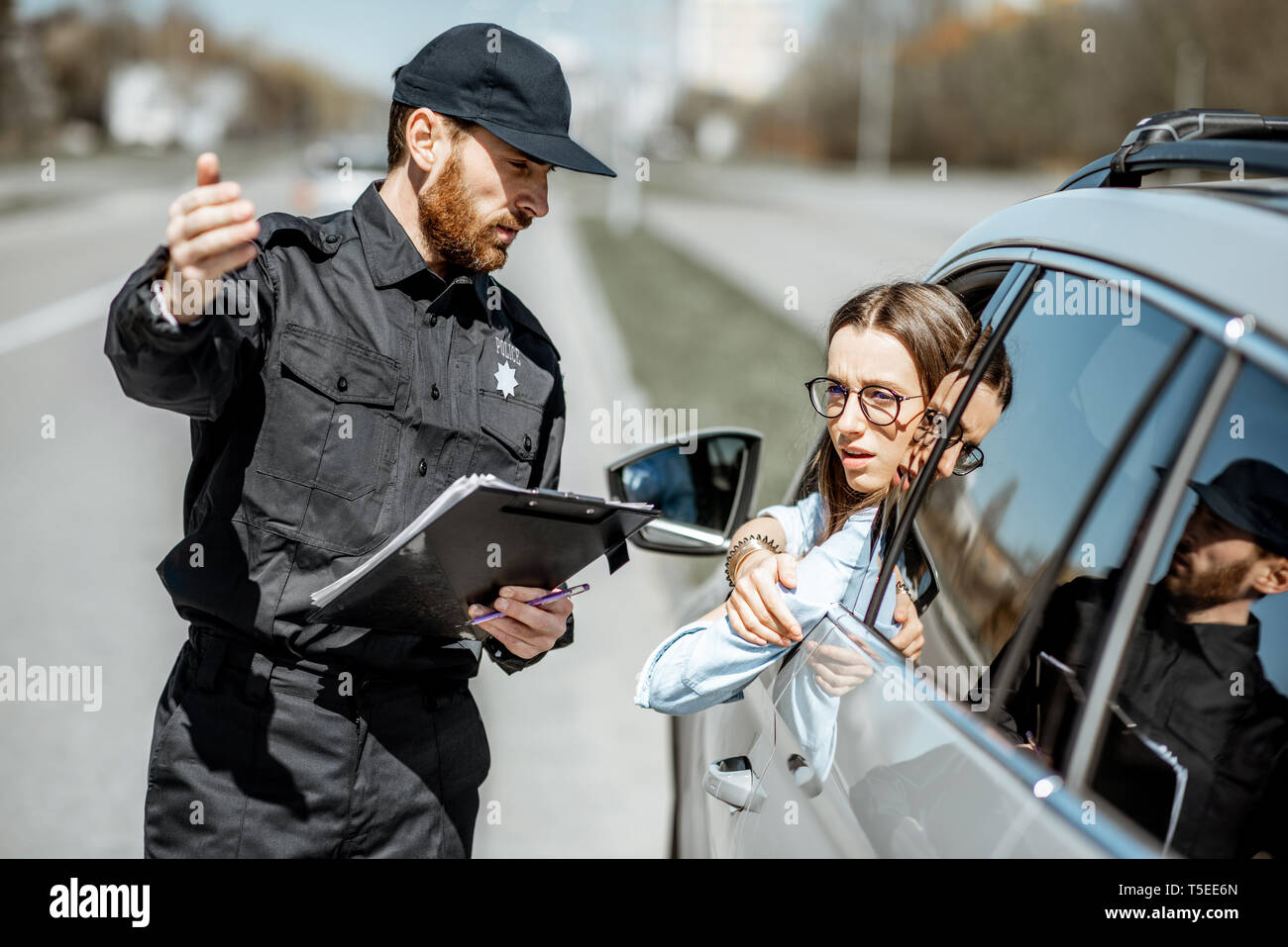 Policeman showing on the road sign while writing out fine for violation ...