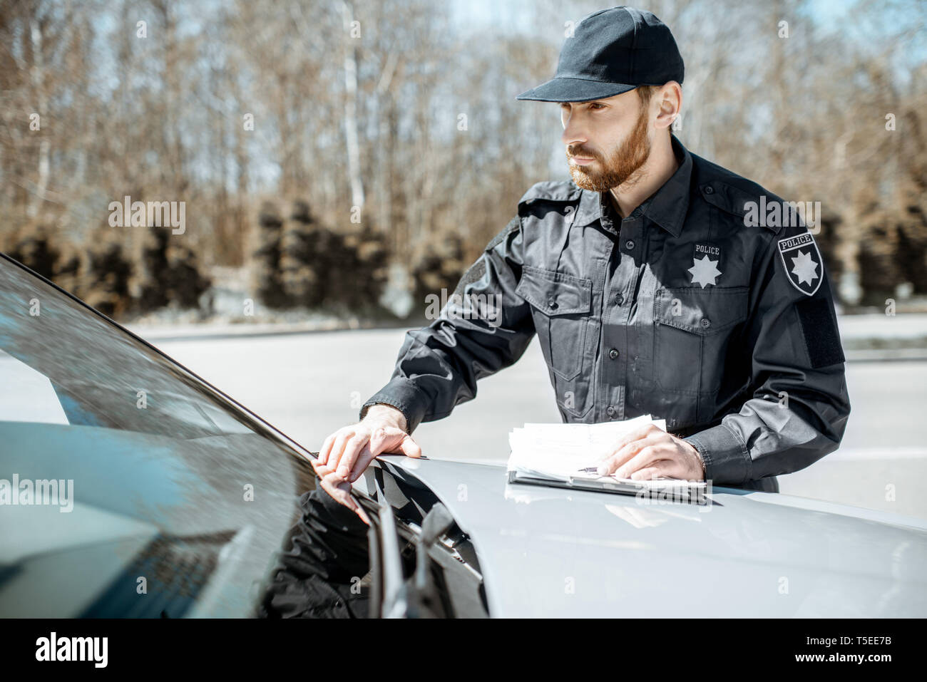 Policeman checking body number of a car, looking on the windshield ...