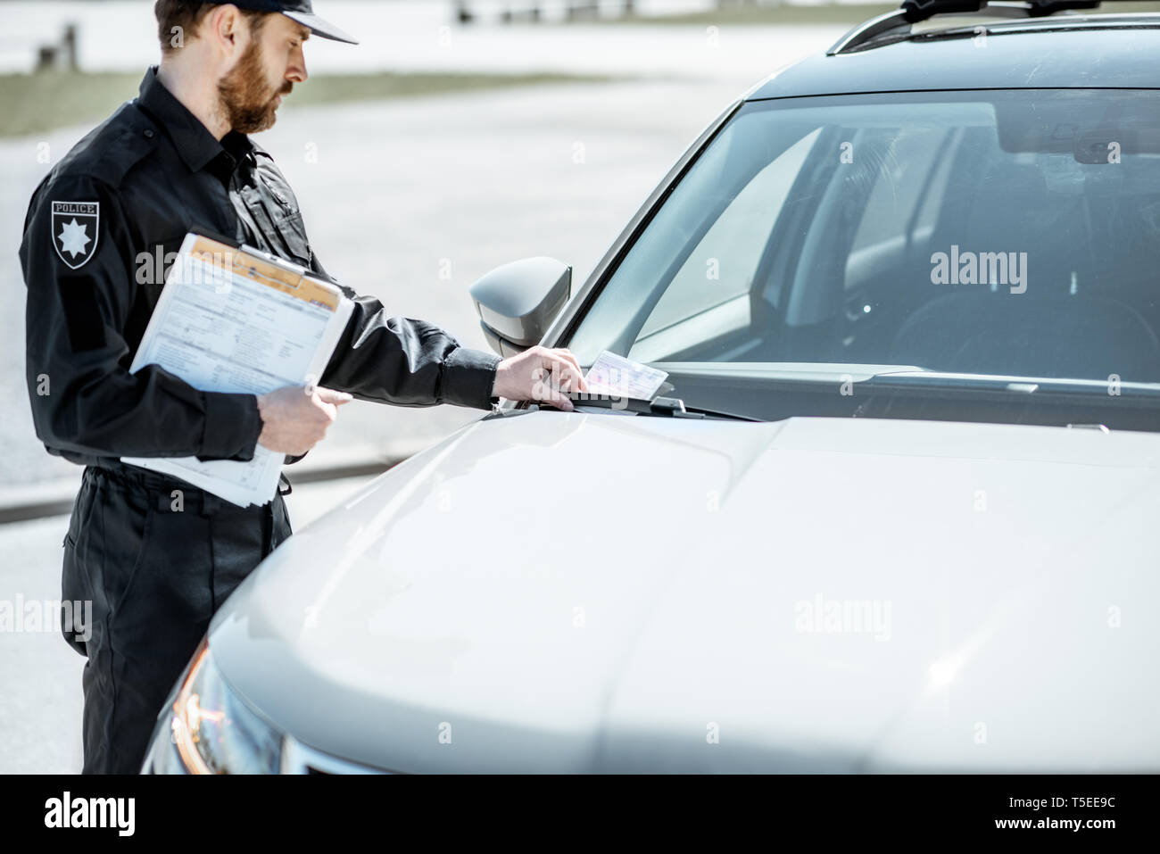 Policeman putting fine for improper parking on the windshield of the ...