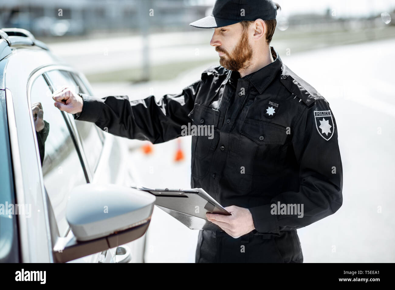 Policeman knocking at the window to a car driver, stopping the car for ...