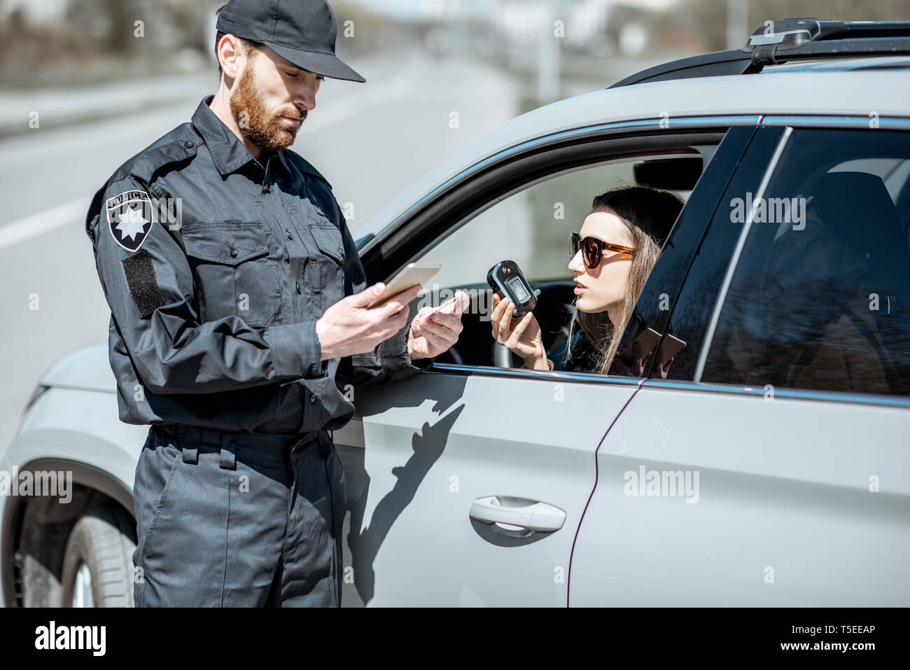 Policeman checking woman driver for alcohol intoxication with special ...