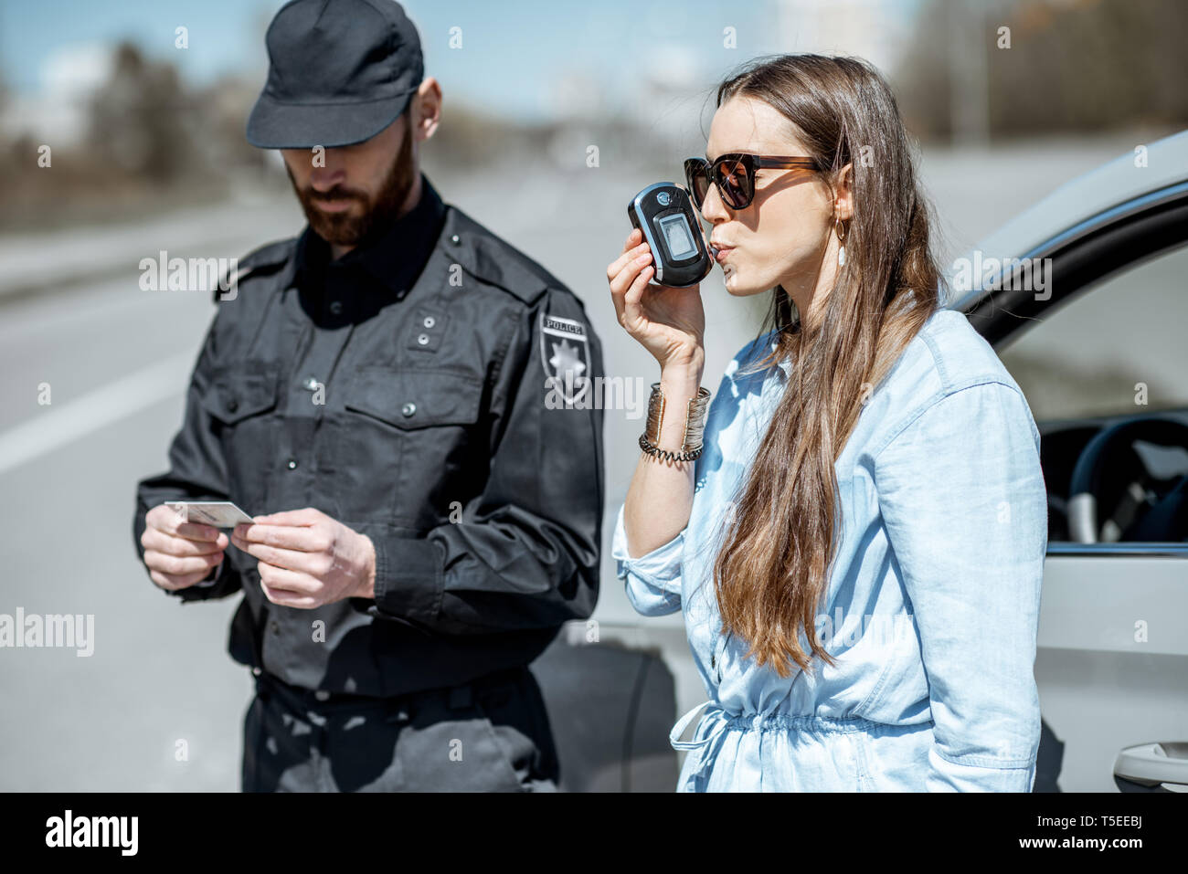 Policeman checking woman driver for alcohol intoxication with special ...