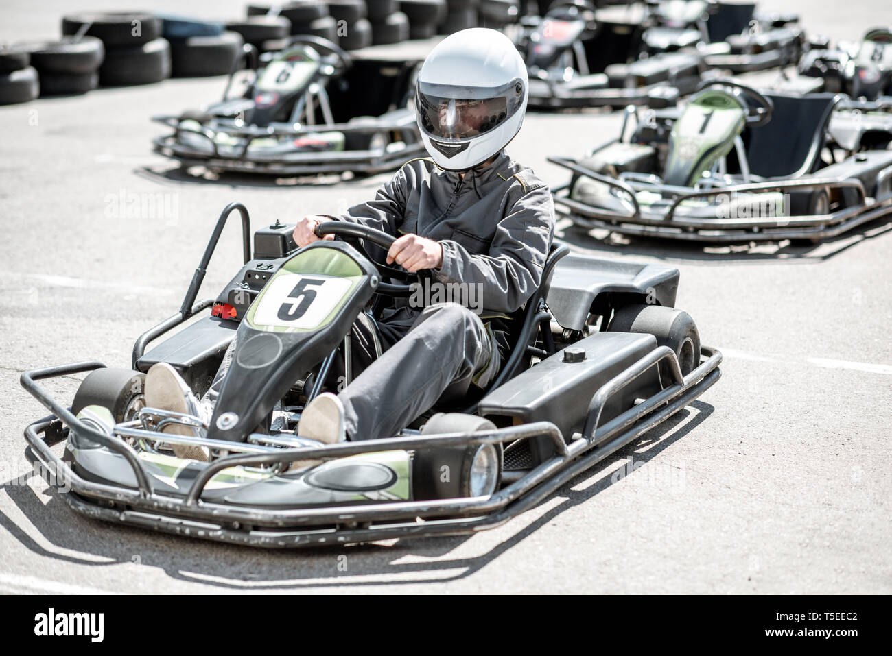 Racer in sportswear and protective helmet driving go-kart on the track ...