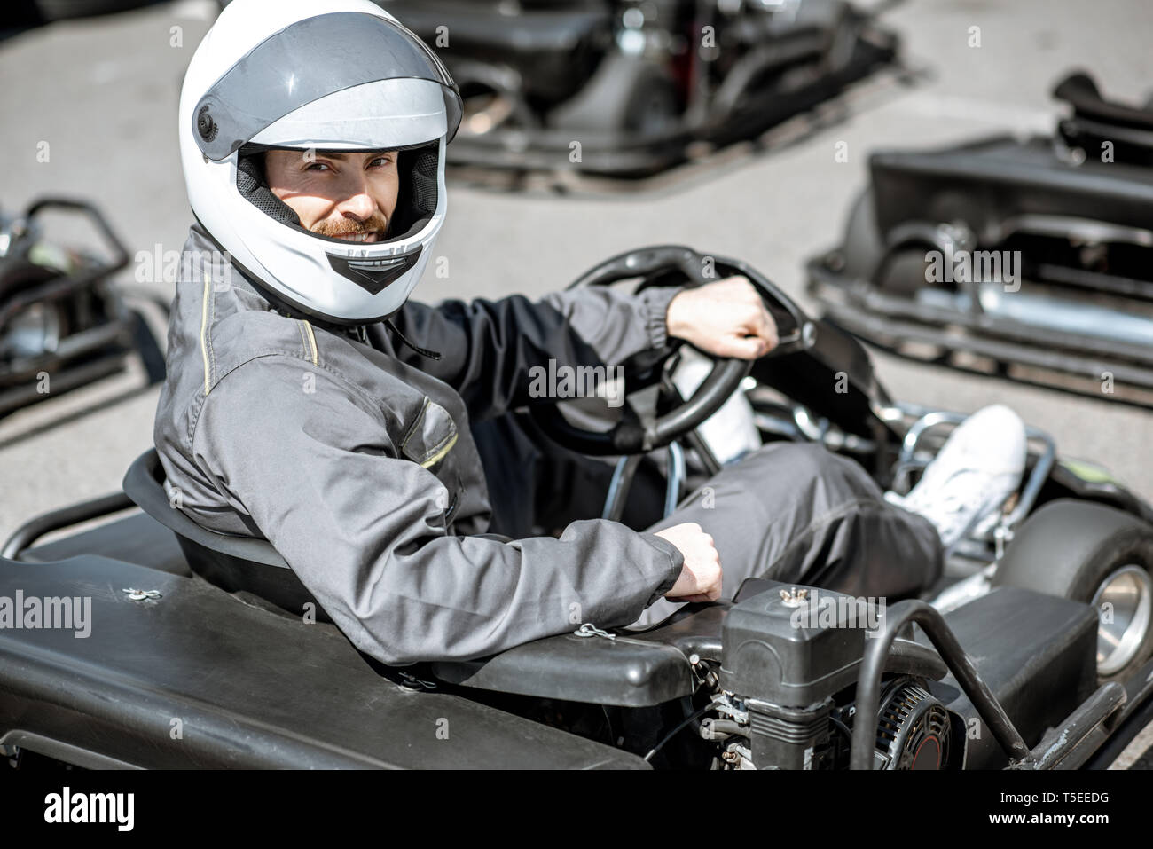 Portrait of a male racer in sportswear and protecive helmet sitting in ...