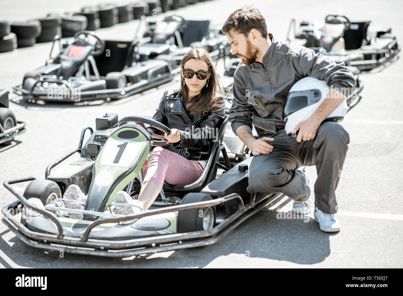 Man in sportswear instructing young woman driver before racing on the ...
